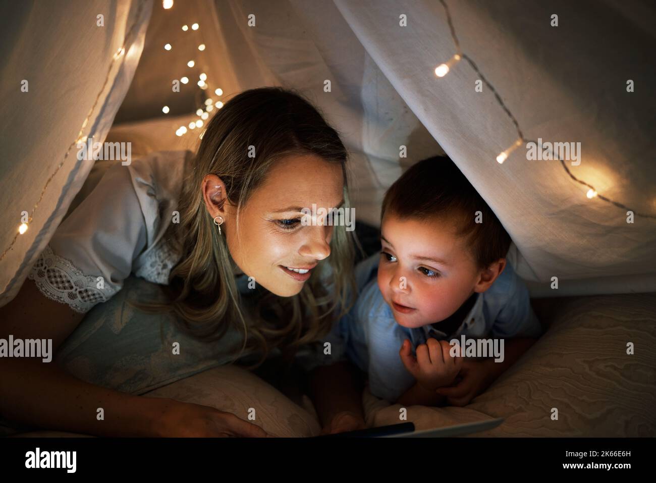 a beautiful young cheerful caucasian woman lying under a blanket fort ...