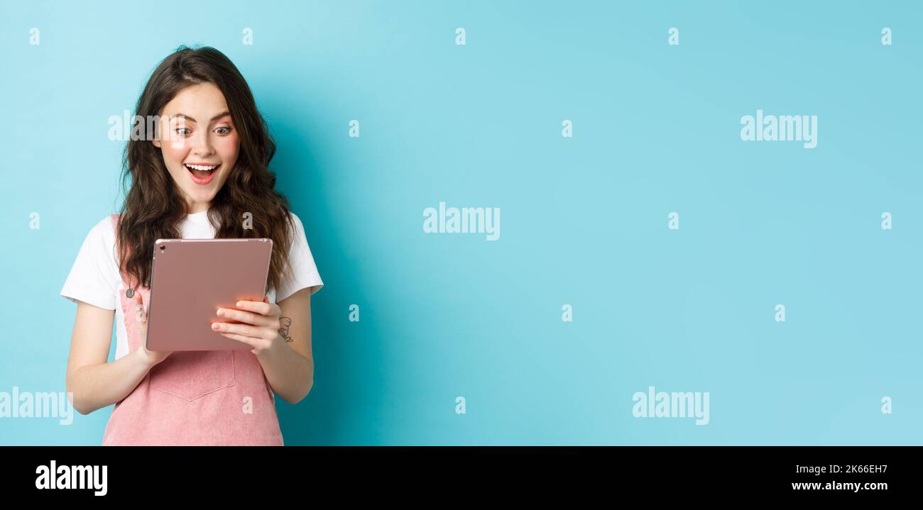 Image of excited young woman stare surprised at digital tablet screen ...