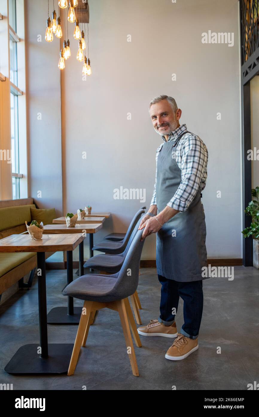 Waiter putting chairs in order in the cafe premises Stock Photo - Alamy