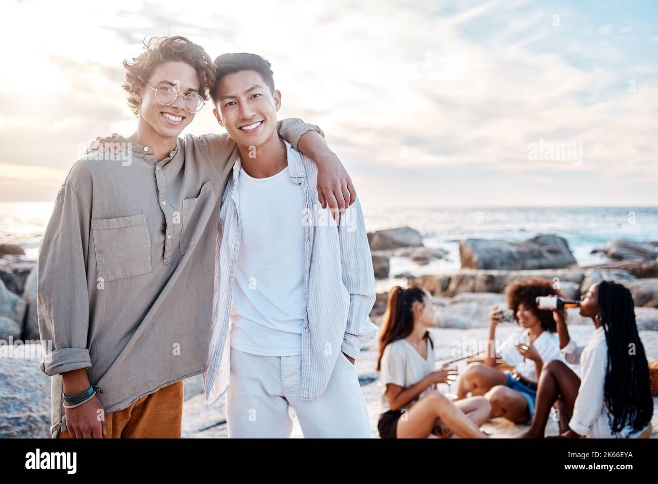 Portrait of two attractive young men standing together on the beach ...