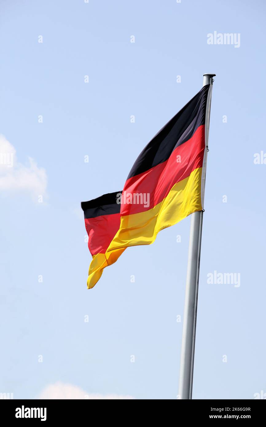 Swinging German flag against blue sky Stock Photo - Alamy