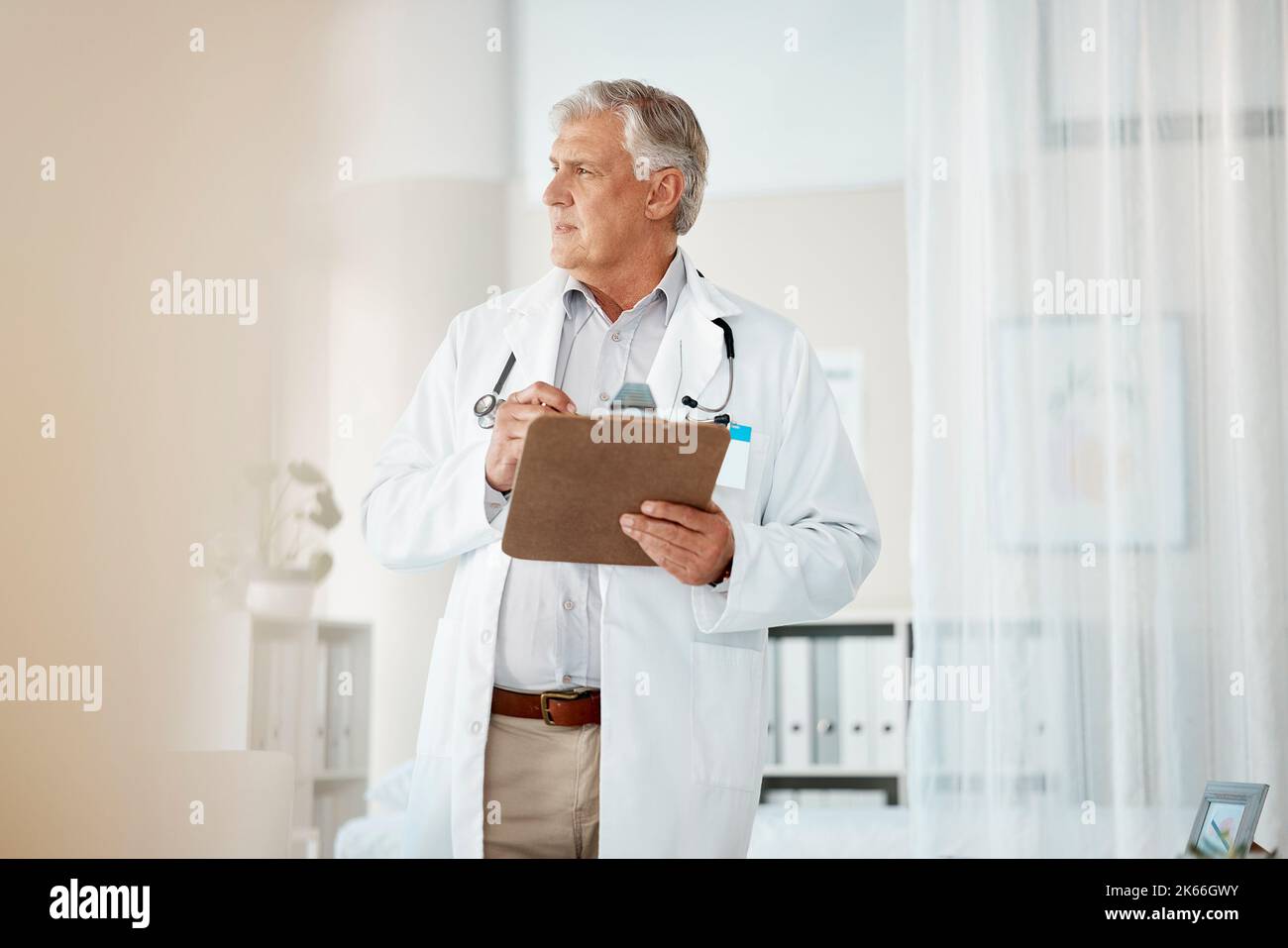 Pensive mature male caucasian doctor in white lab coat looking out ...