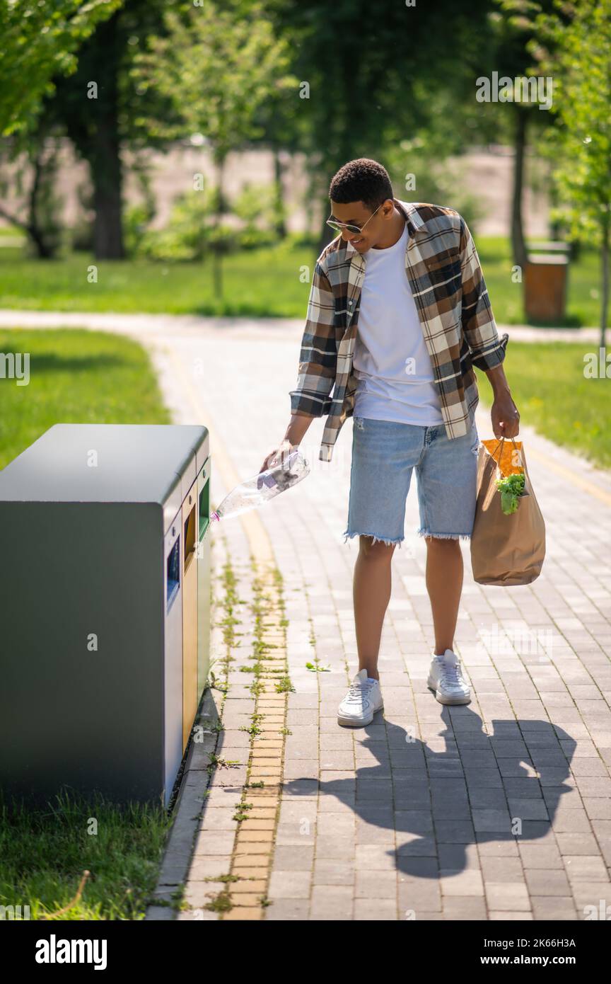 Young african american man throwing plastic bottle to the trash can ...