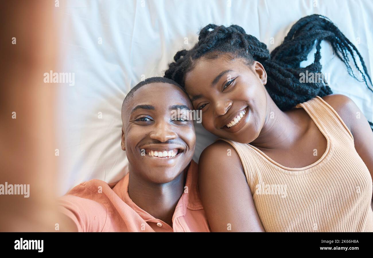 Closeup of happy african american couple taking a selfie while lying on their together. Young ...