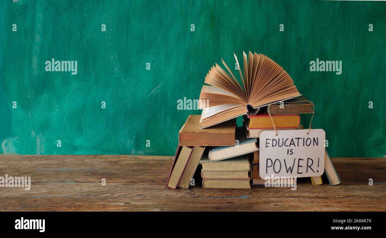 Open book, hardback books with education is power sign on teal ...