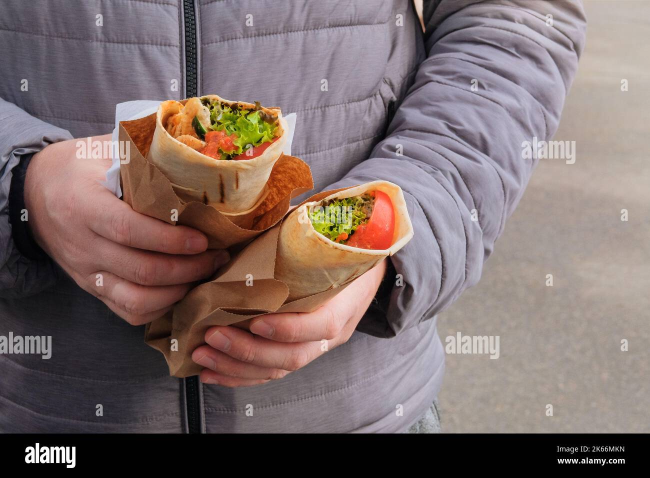 Shawarma takeaway. Roasted meat with vegetables and sauce. Hand is ...