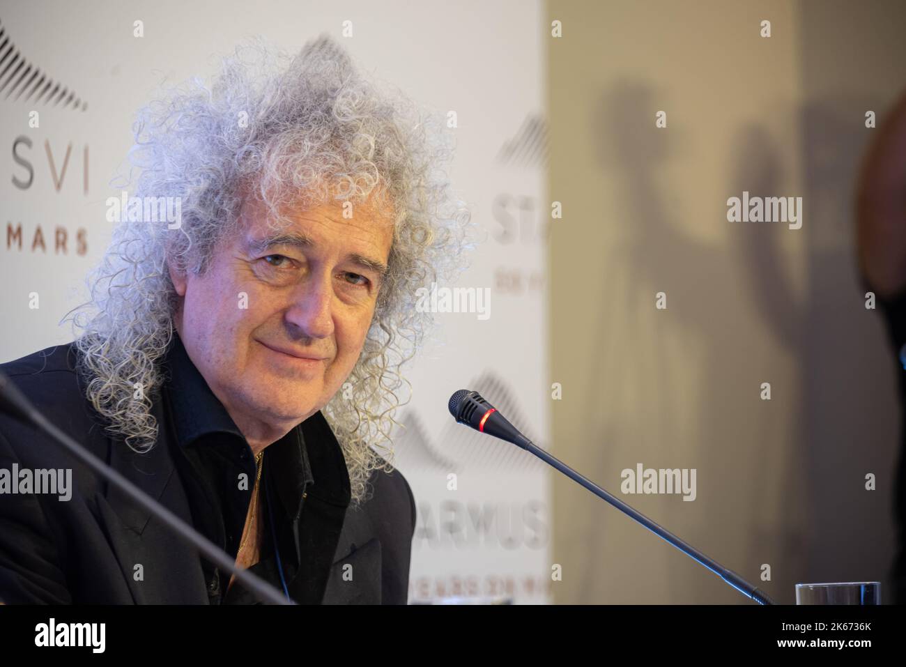 A portrait of Brian May smiling and looking into the camera with ...