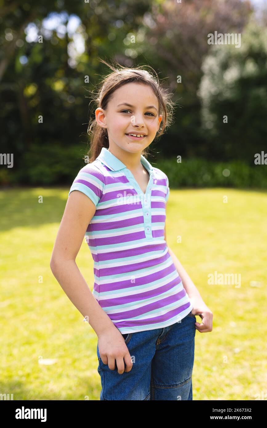 Vertical portrait of young caucasian girl wearing striped t-shirt and ...