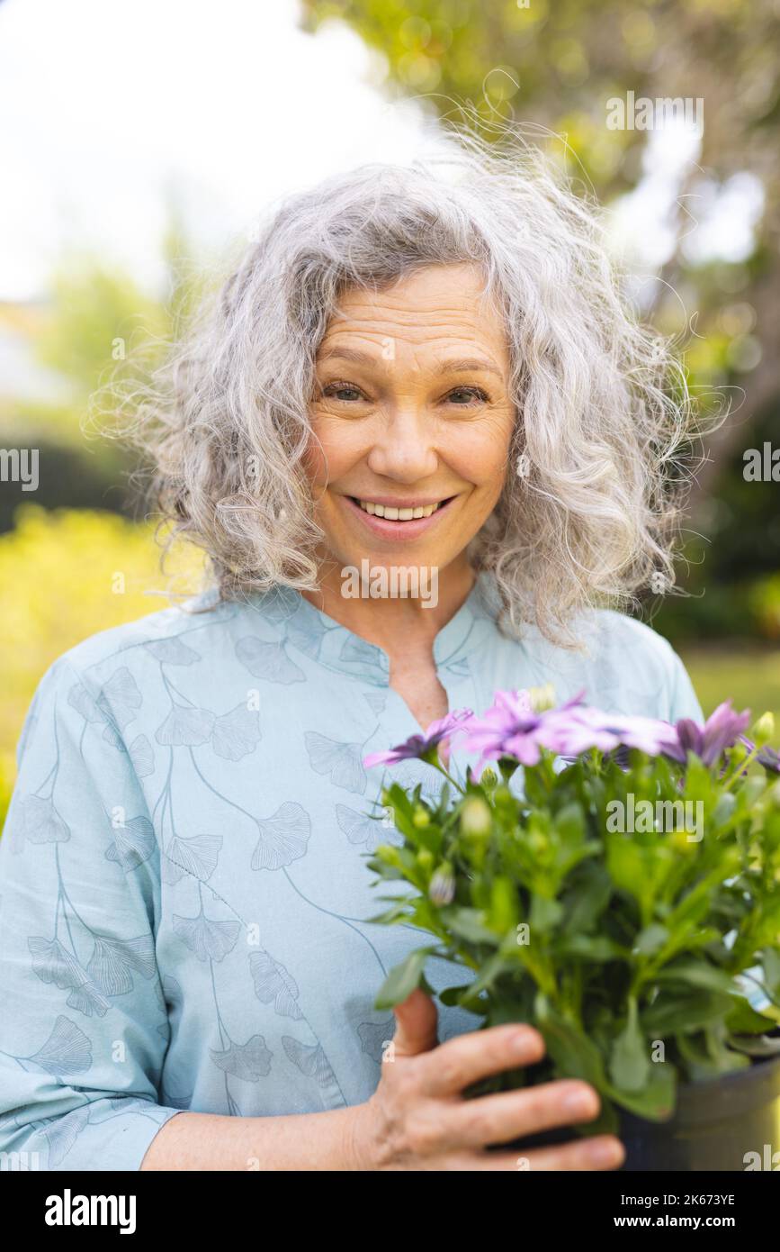Vertical portrait of caucasian senior women spending time in the garden ...