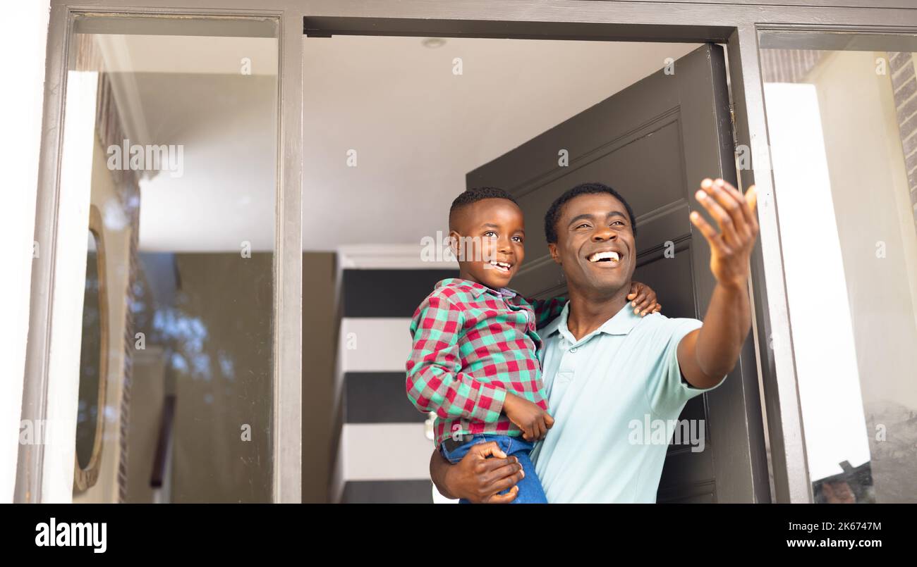 African american father and son welcoming some body outside the house ...
