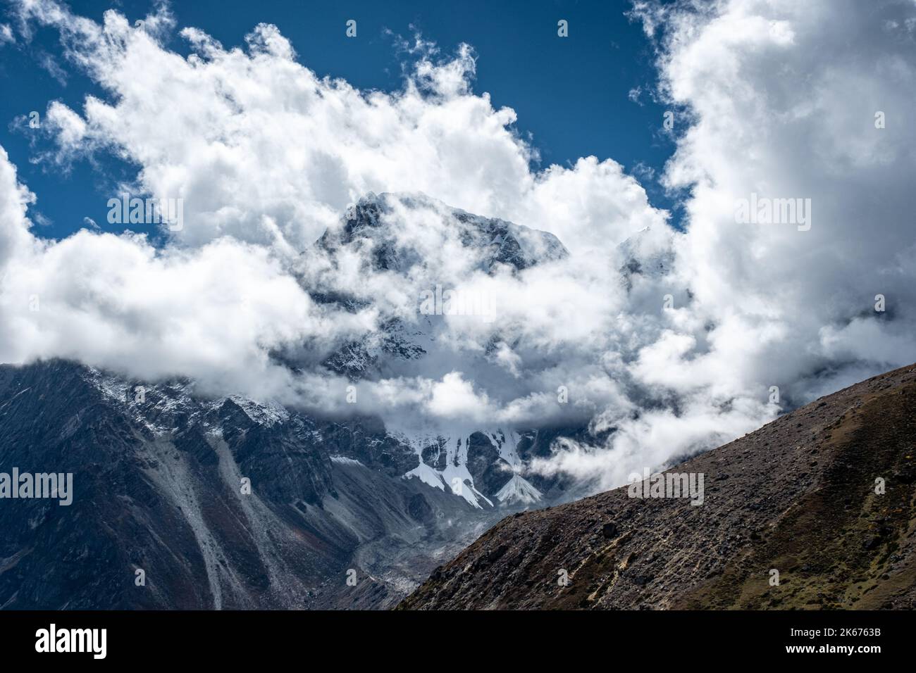 The summit of Himalayan snow caped mountains with dramatic clouds, on ...