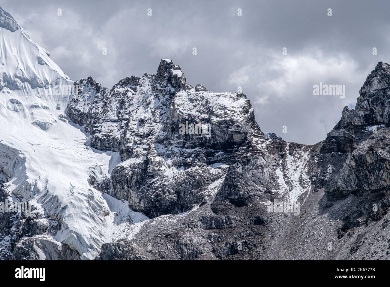The clouds part to reveal snow capped ridges in dramatic light, high ...
