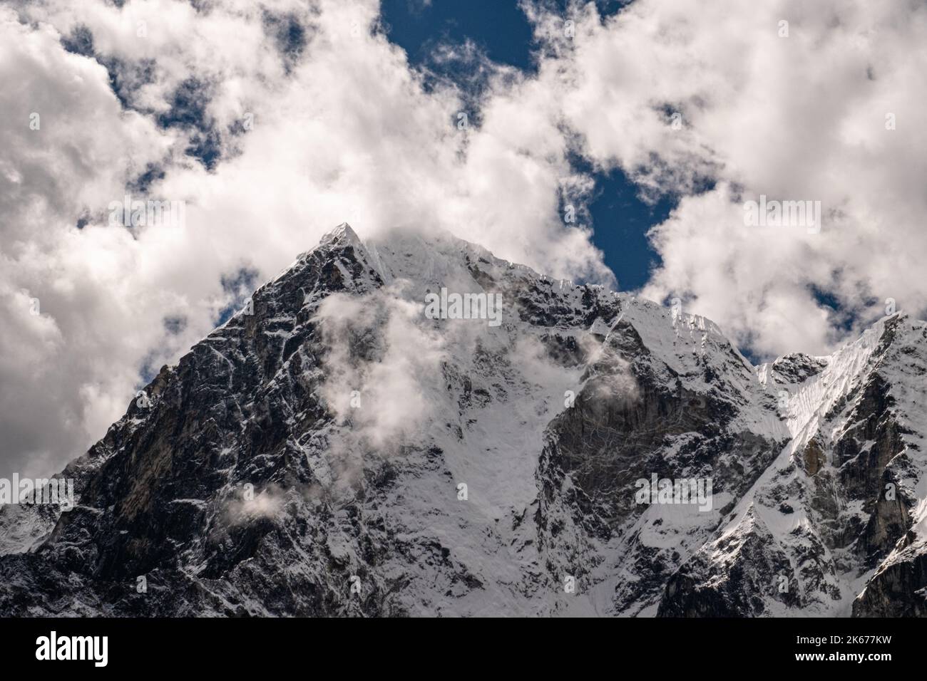 The summit of Himalayan snow caped mountains with dramatic clouds, on ...