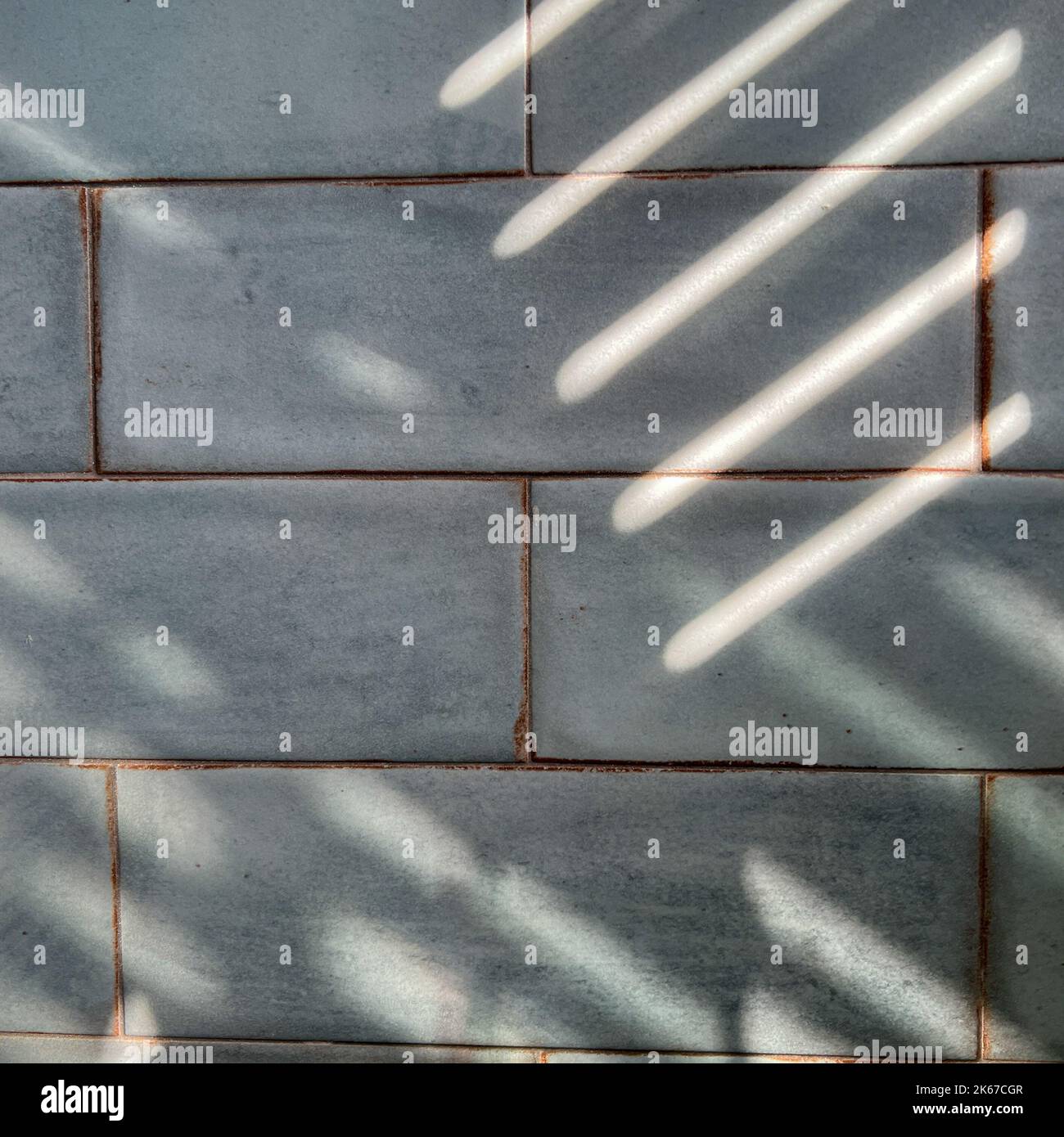 A tile wall in a bathroom with shadows which can be used as a ...