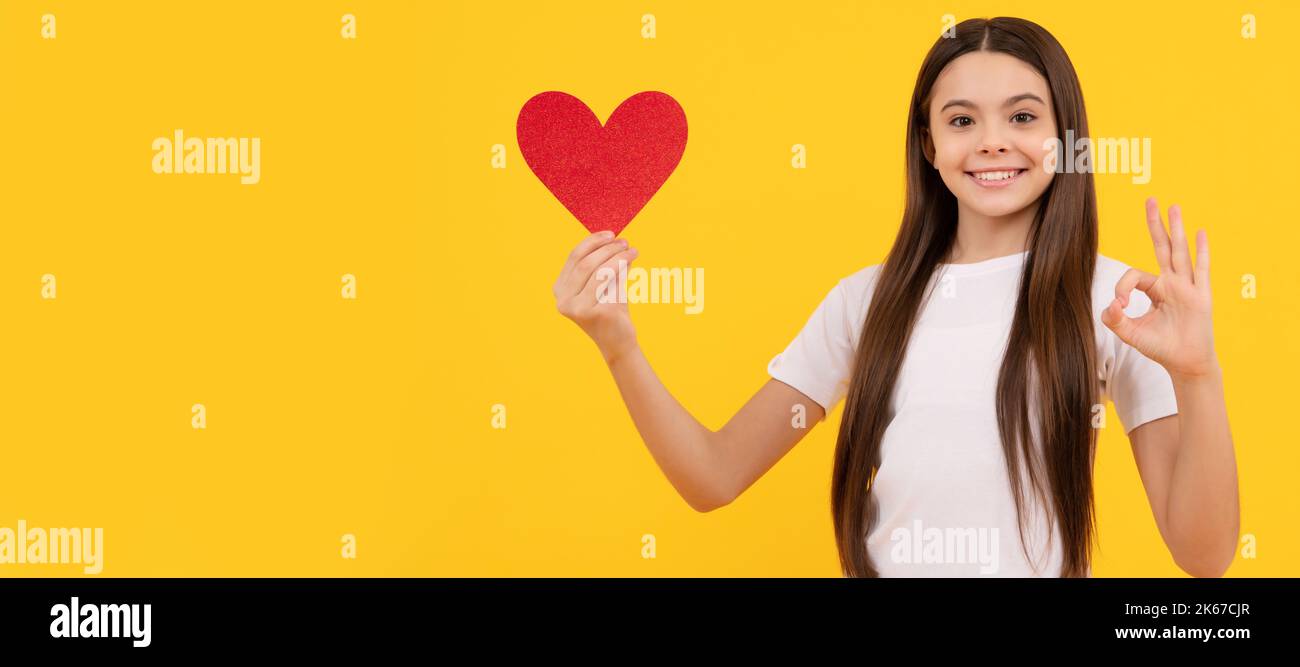 happy teen girl holding valentines heart showing ok gesture on yellow ...
