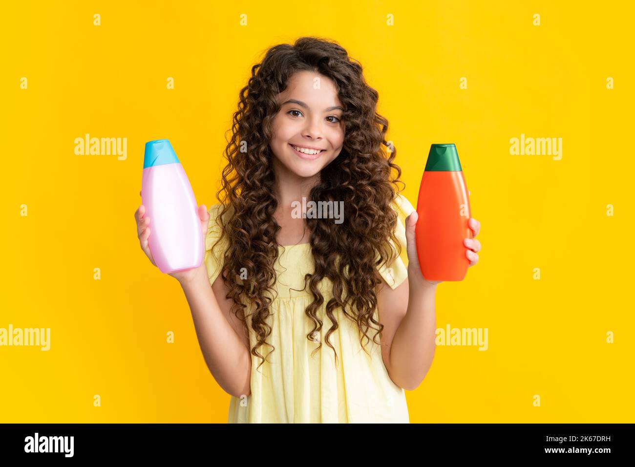Happy teenager, portrait of child girl with bottle shampoo conditioners ...