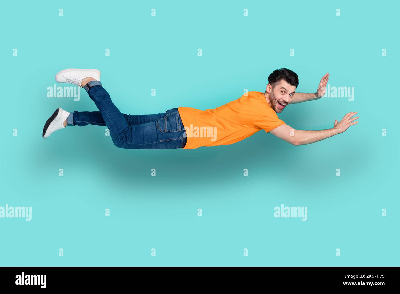 Full length photo of crazy guy levitating in air wind isolated on cyan ...
