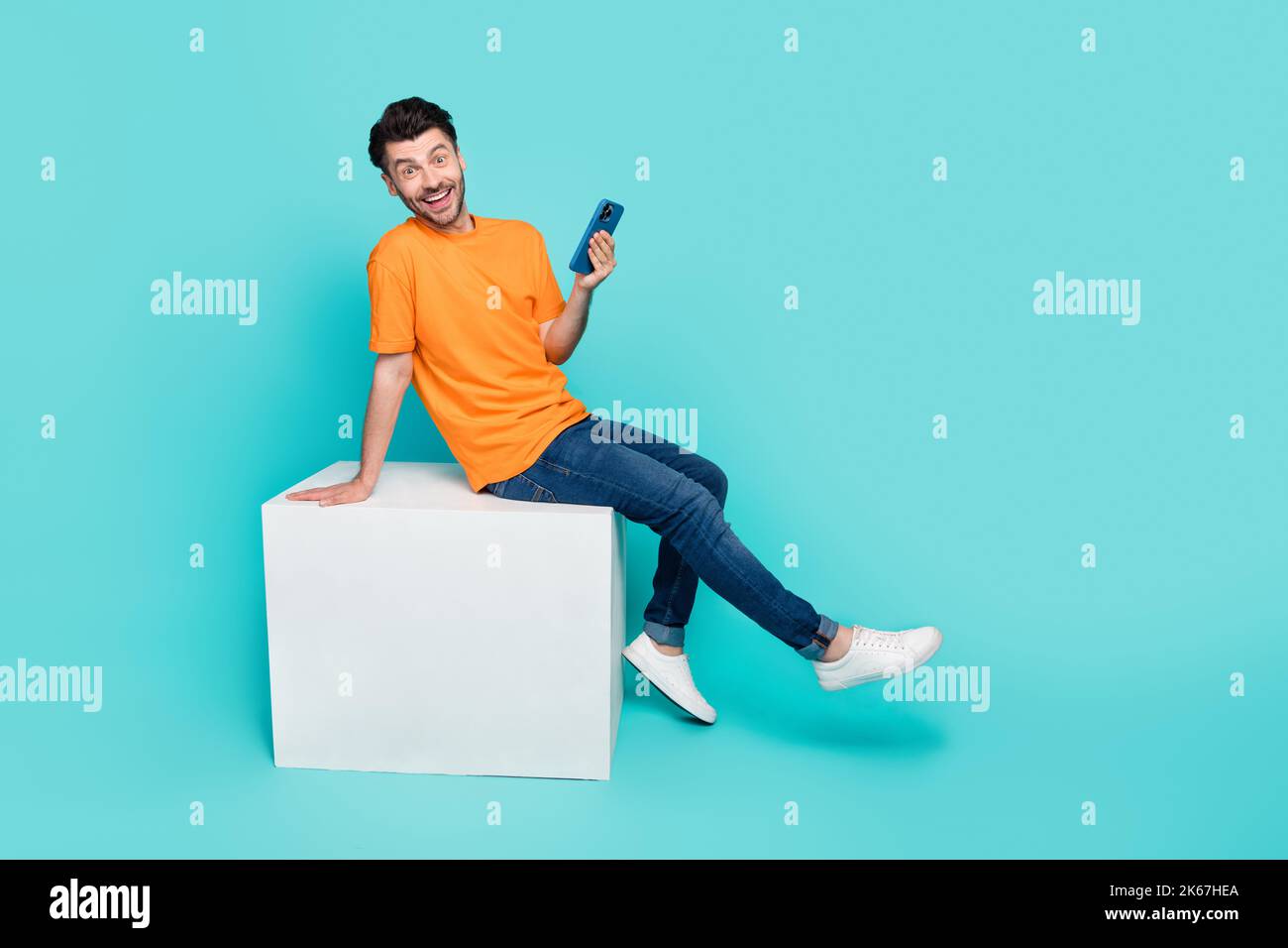Full body profile side photo of excited guy sit white cube using gadget ...