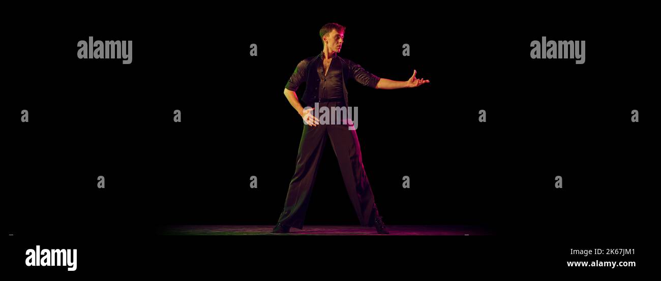 One young man, flexible male dancer in black costume standing alone ...