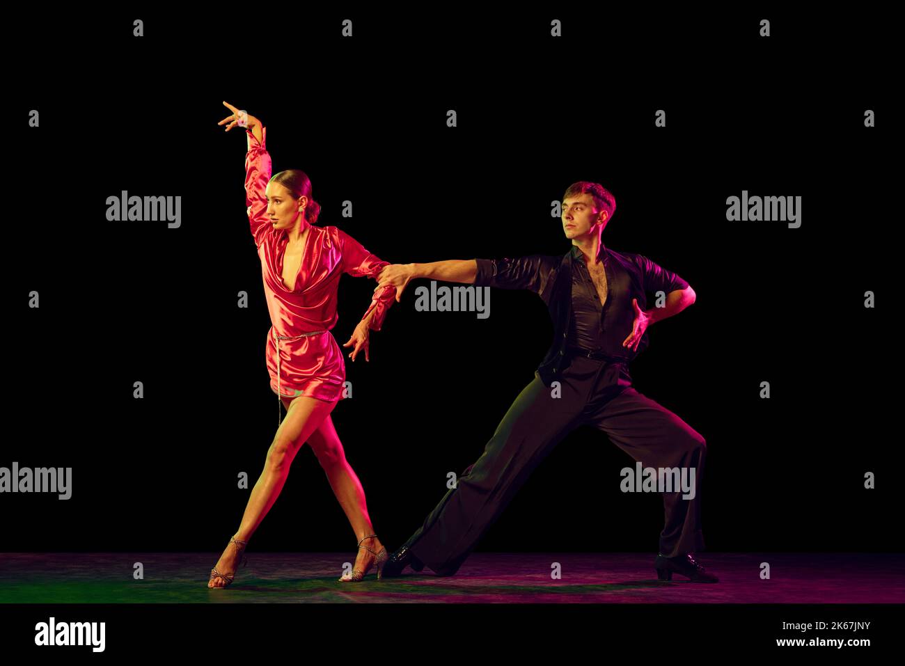Full-length portrait of young beautiful man and woman dancing ballroom ...