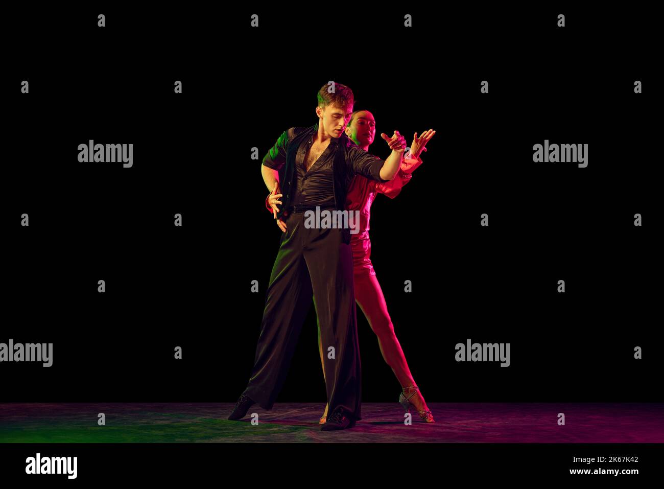 Full-length portrait of young beautiful man and woman dancing ballroom ...