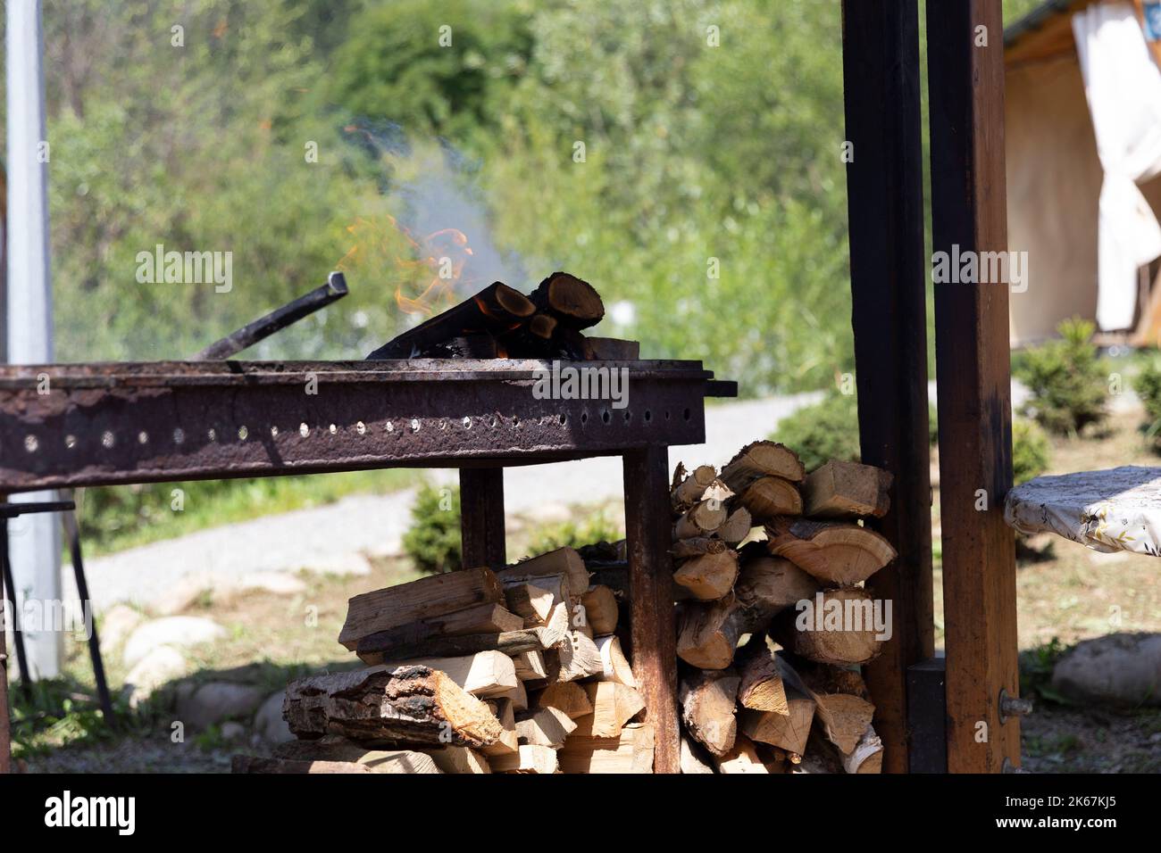 Old barbecue grill with burning wood logs. Open fire from a metal box ...