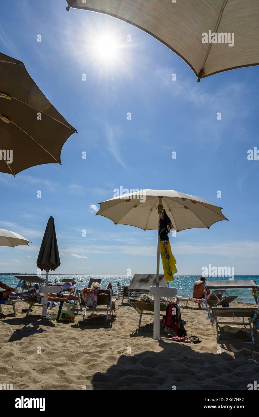 Sunbathers and beachgoers with sunbeds and parasols on Sottovento beach ...