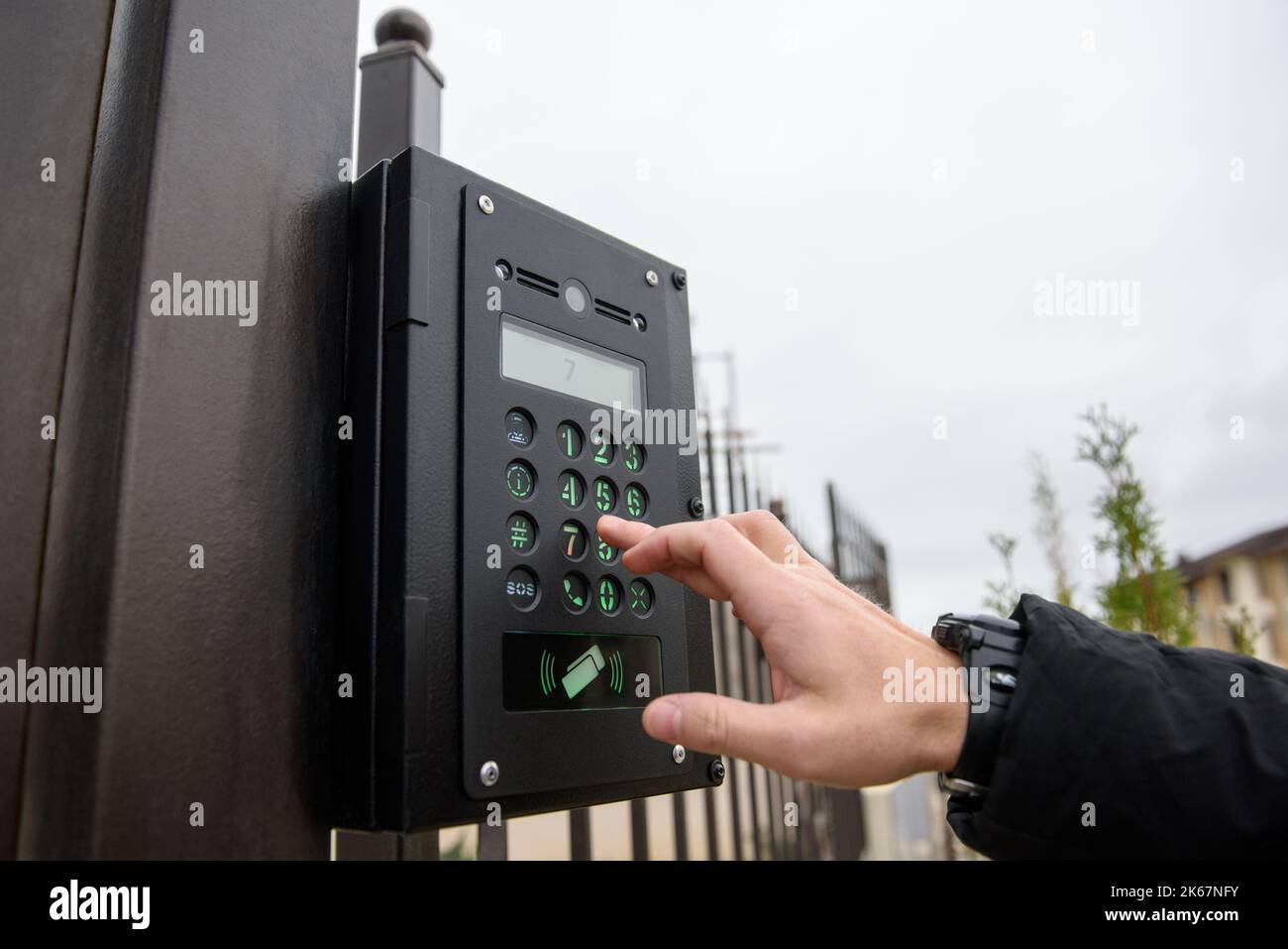 A person's hand reaches for an intercom with camera installed on a ...