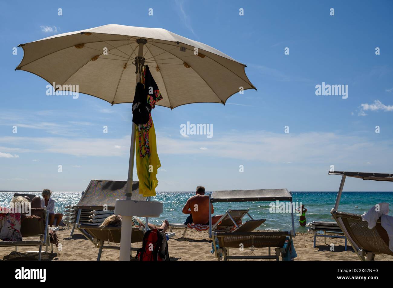 Sunbathers and beachgoers with sunbeds and parasols on Sottovento beach ...