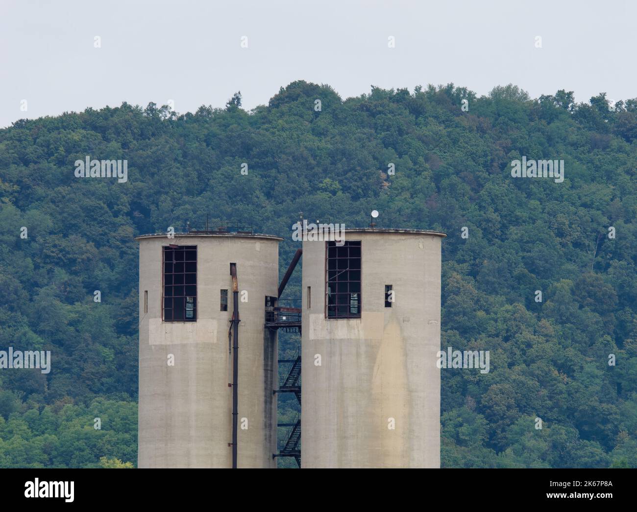 Two tall factory chimneys with a background of a forested mountain ...