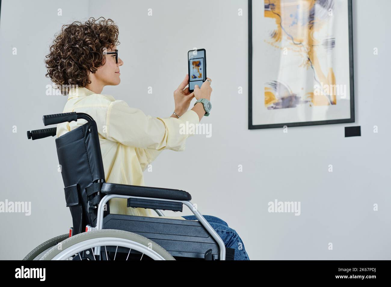Young woman with disability making photo of modern art on her mobile ...