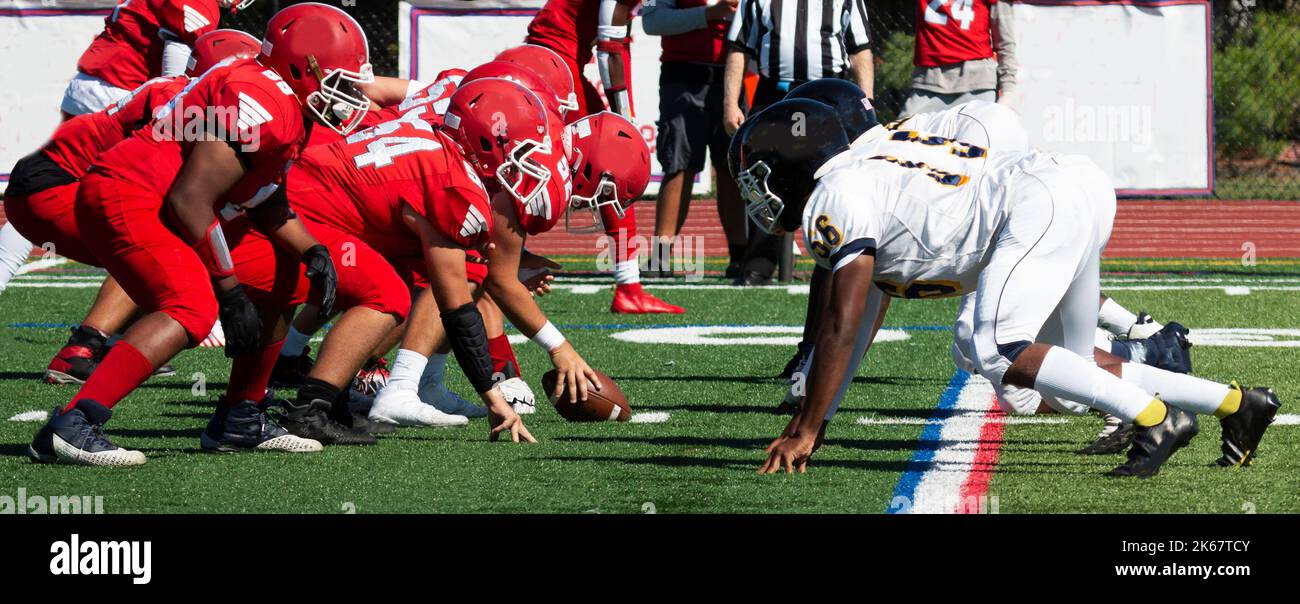 Side view of two high school football teams lined up for the snap of ...