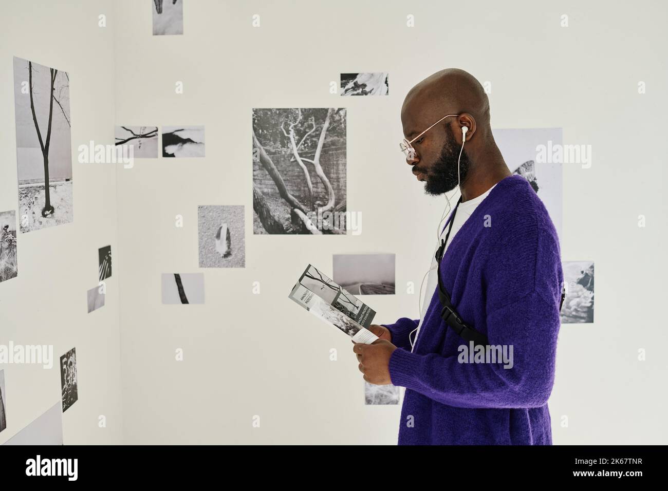 African man in headphones reading booklet while examining pictures at ...