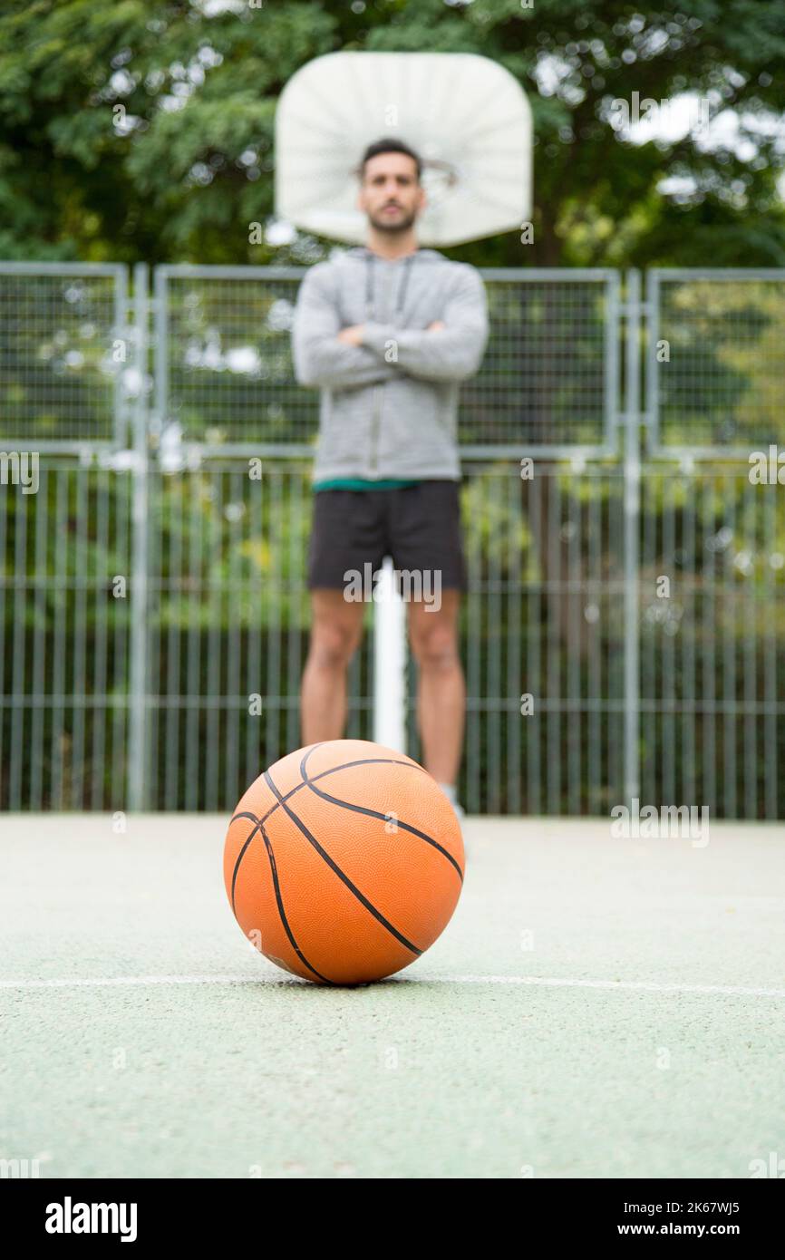 Focus on a basketball ball on a outdoor court with a basketball player ...