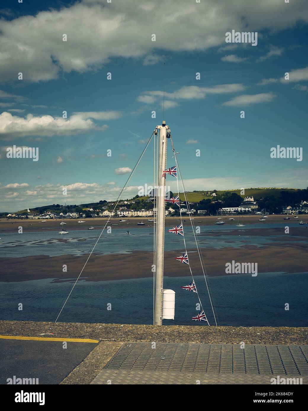 A vertical shot of the sailboat mast with small British flags seen from ...