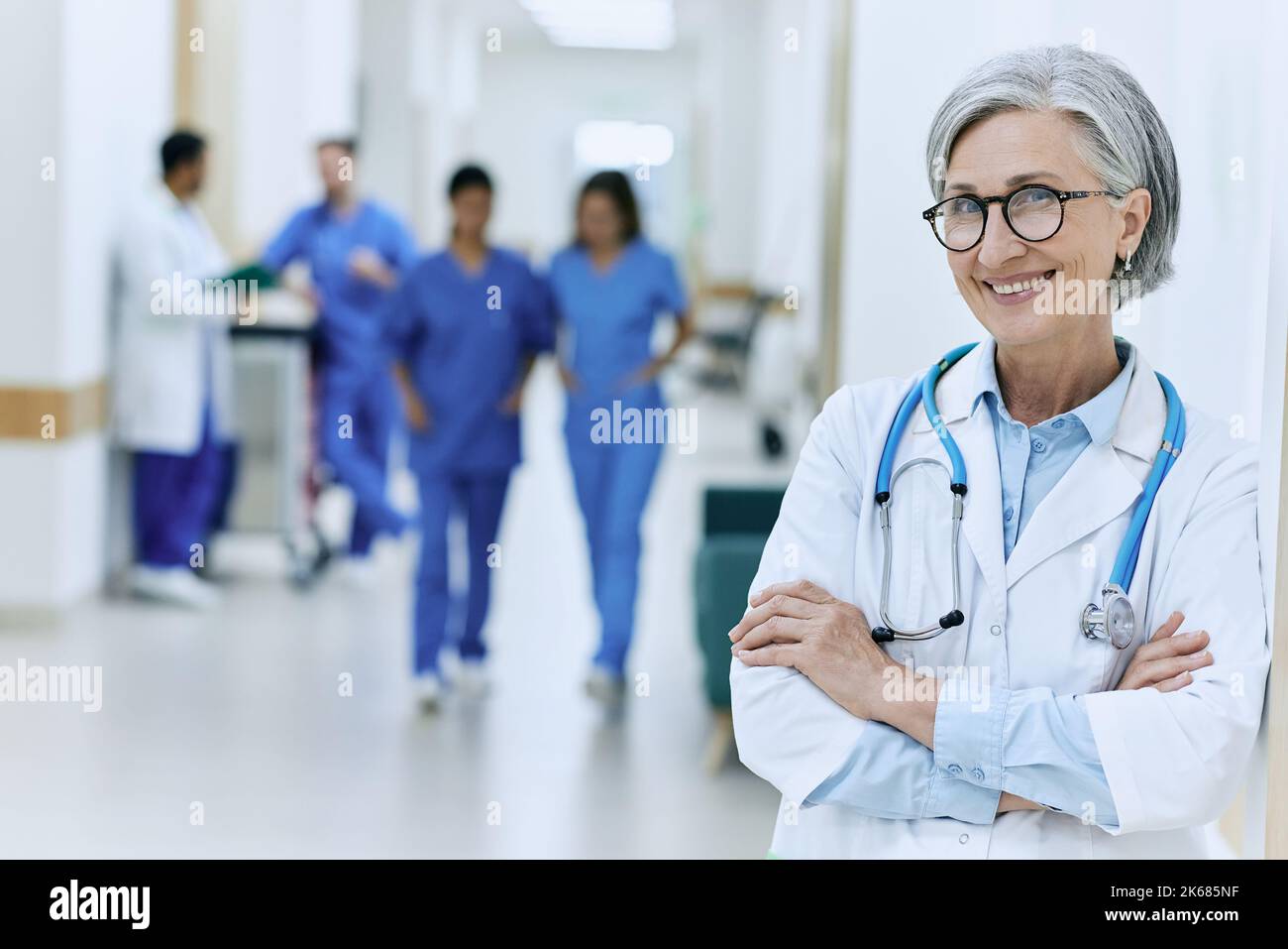 Mature female general practitioner with stethoscope standing in medical ...