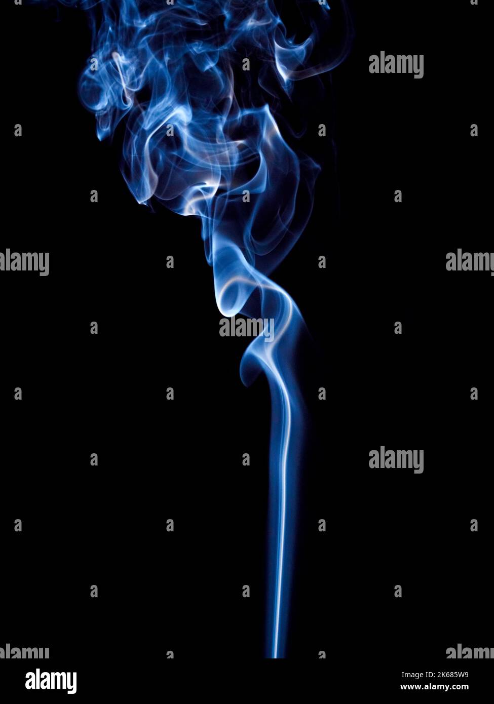 A thin stream of blue smoke curls and rises spectacularly over a black ...