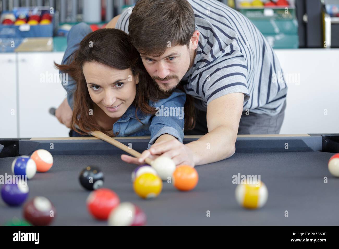 woman receiving advice on shooting pool ball while playing billiards ...