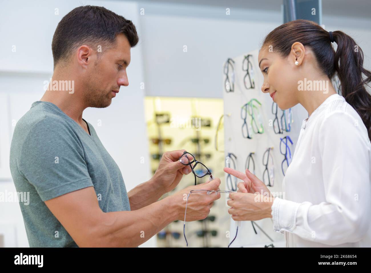 woman selling eyeglasses to customer man in glasses store Stock Photo ...
