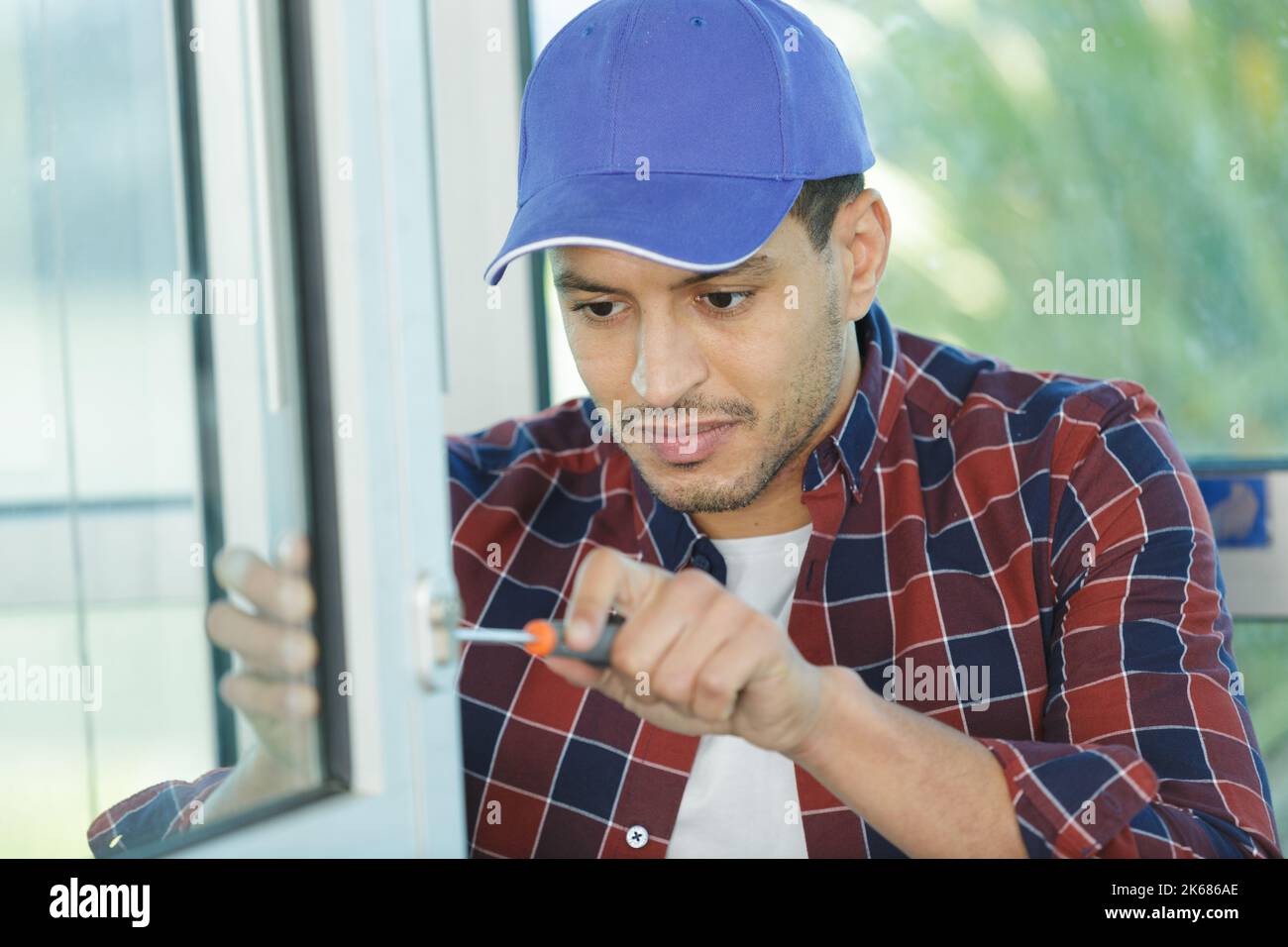 service man installing window with screwdriver Stock Photo - Alamy