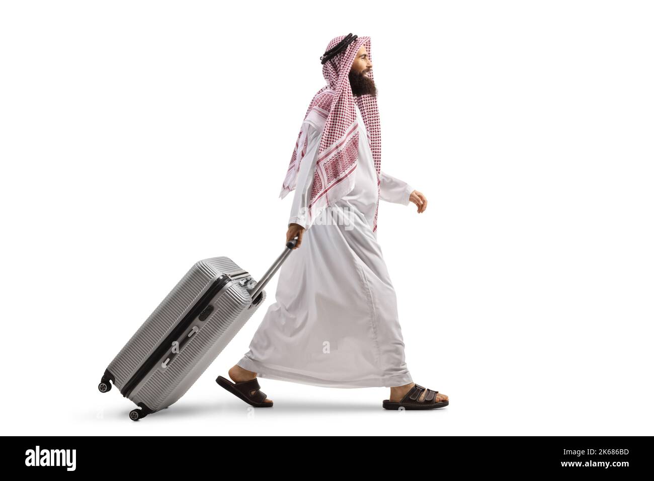 Full length profile shot of a saudi arab man walking and pulling a ...