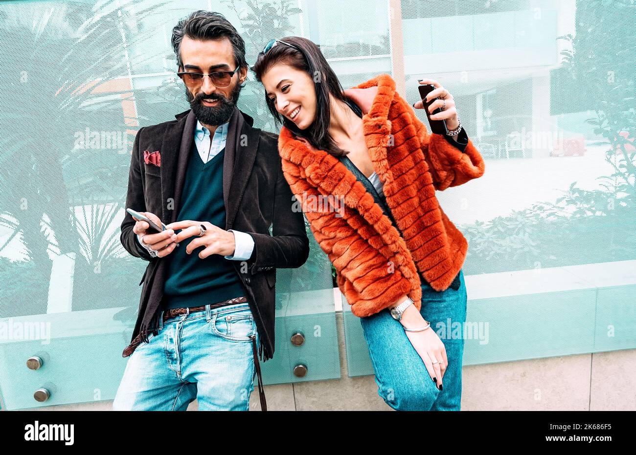 Modern hipster couple having fun using mobile smart phone outside ...