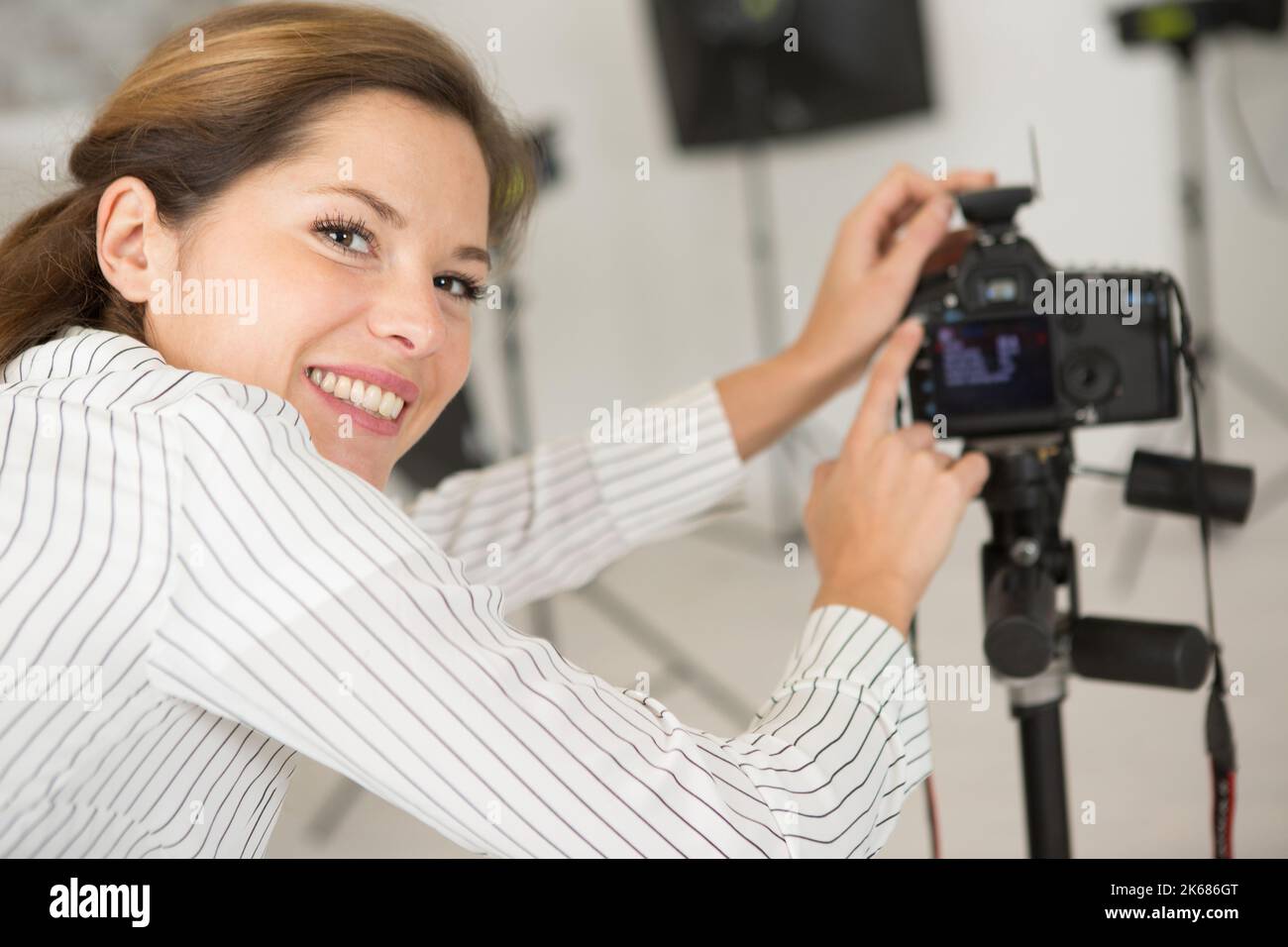 female photographer adjusting her camera during studio shoot Stock ...