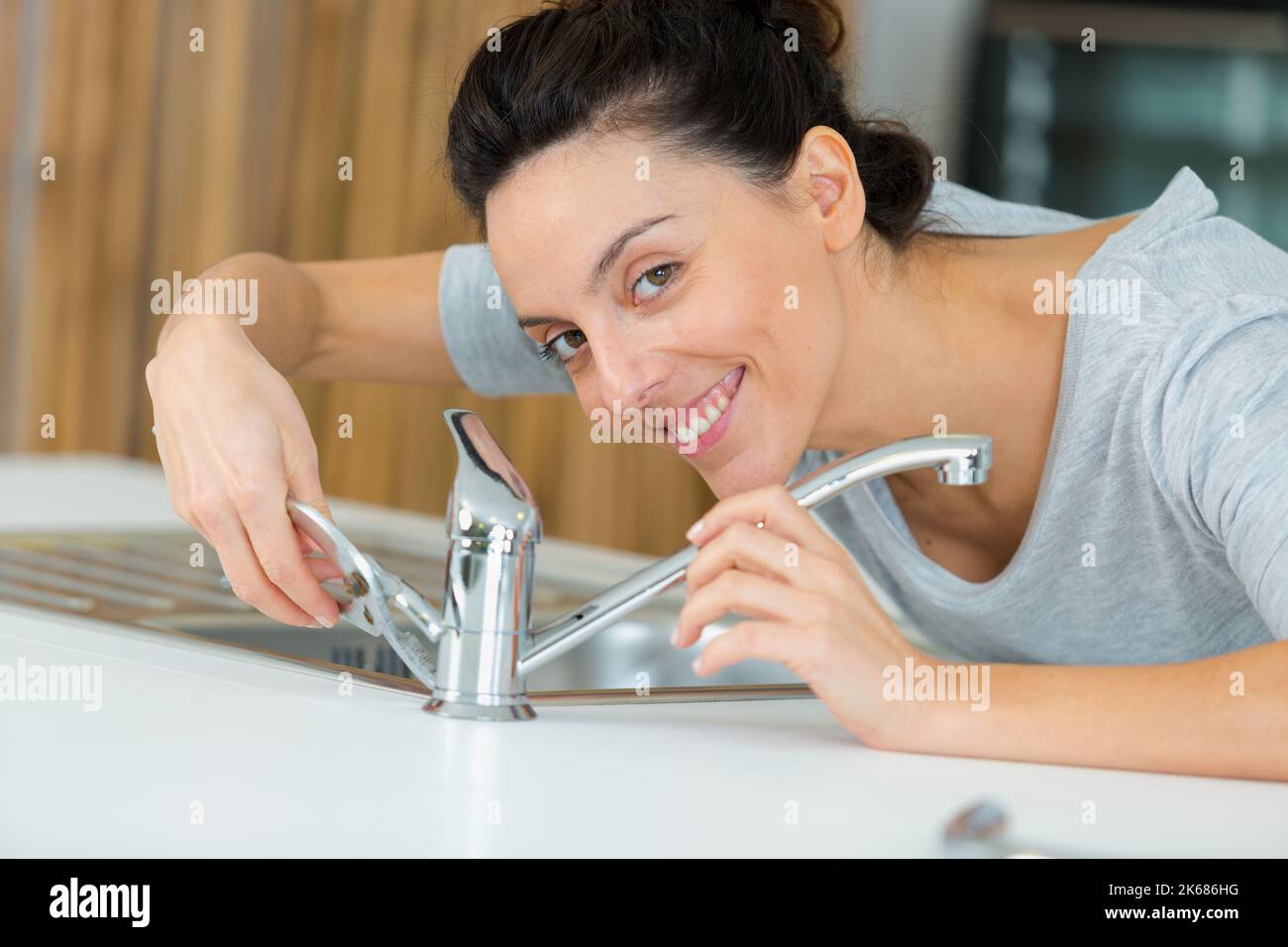 portrait of lady fixing kitchen tap Stock Photo - Alamy