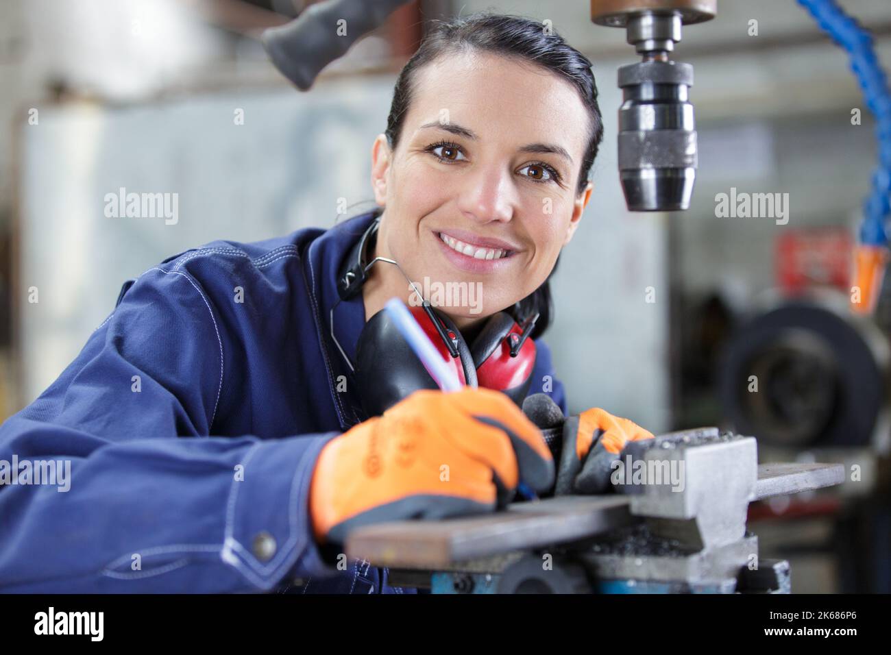 female apprentice using drill in factory Stock Photo - Alamy