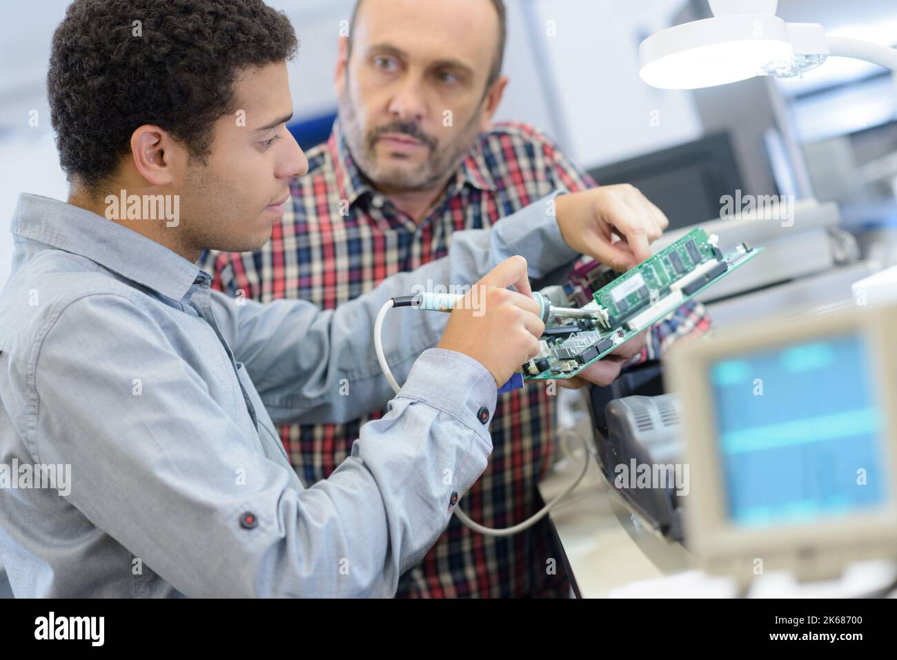 apprentice and teacher chip soldering Stock Photo - Alamy