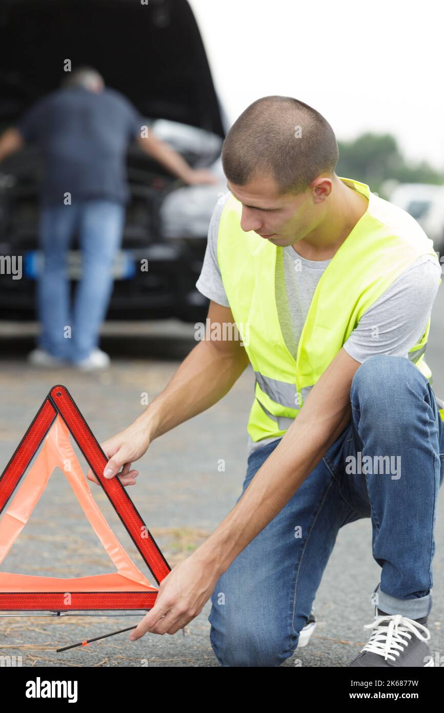 young man putting warning triangle behind his broken down car Stock ...