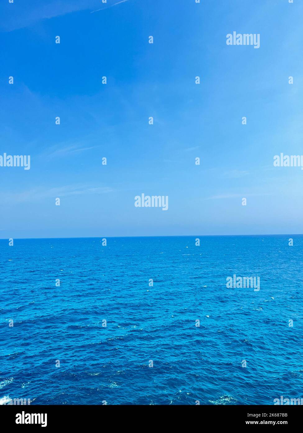 A breathtaking view of clear blue sky and calm ocean merging into the ...
