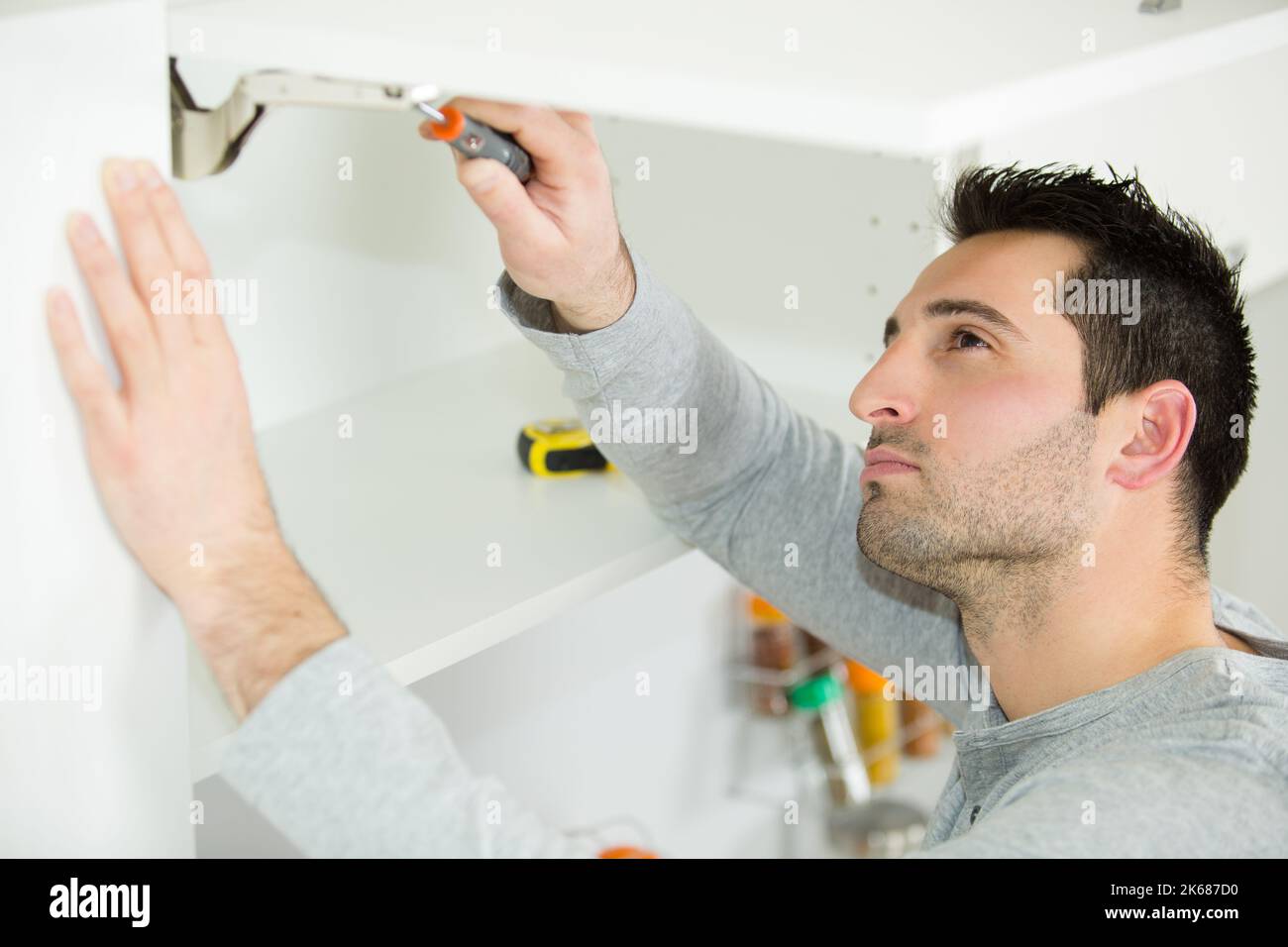 man fitting an overhead kitchen cupboard Stock Photo - Alamy