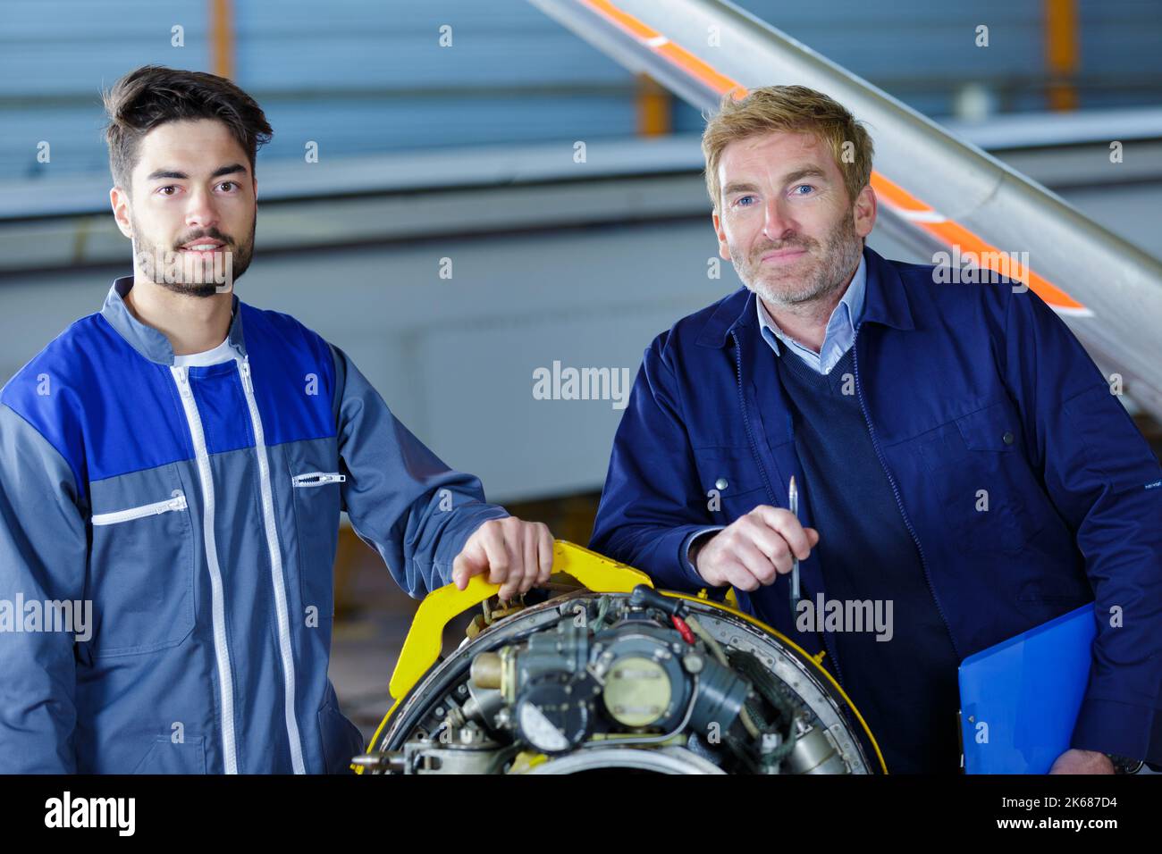 two flight engineers posing in a large aircraft hangar Stock Photo - Alamy